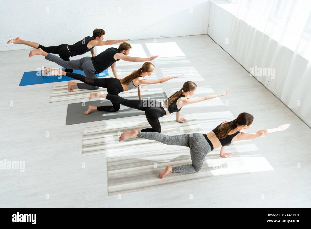 high angle view of five young people practicing yoga in balancing table ...