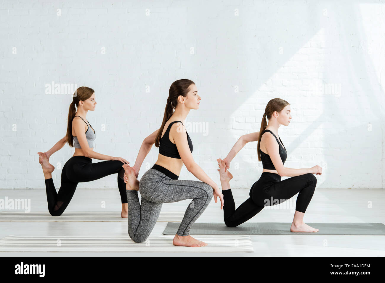 side view of three young women practicing yoga in mermaid pose Stock ...