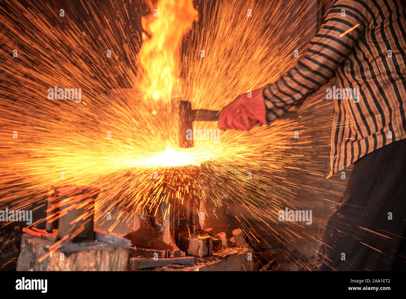 Blacksmith forging the molten metal with a hammer to make keris in the ...