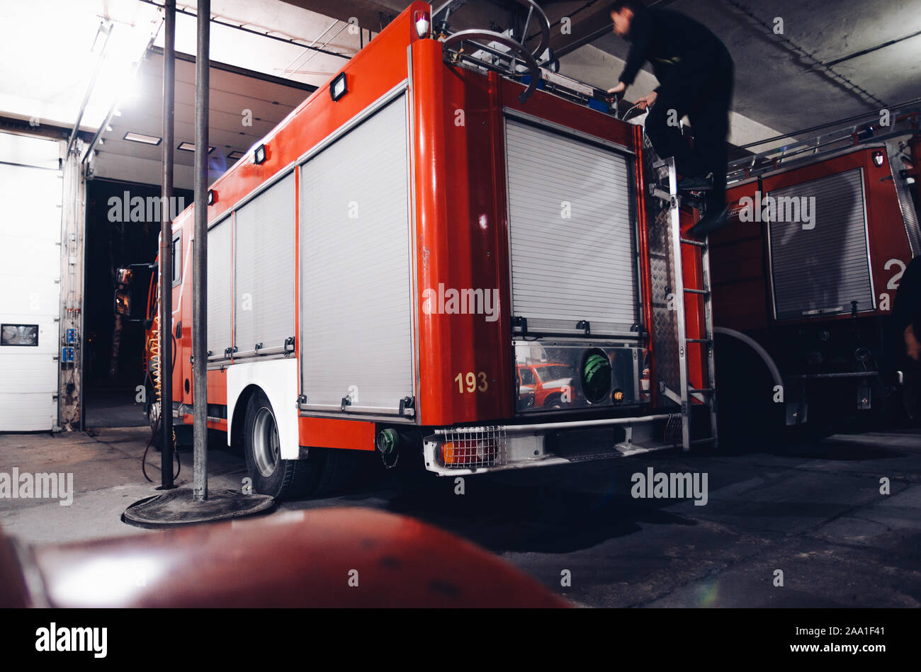 Firefighter climbing a truck equipped various tools for firefighting ...