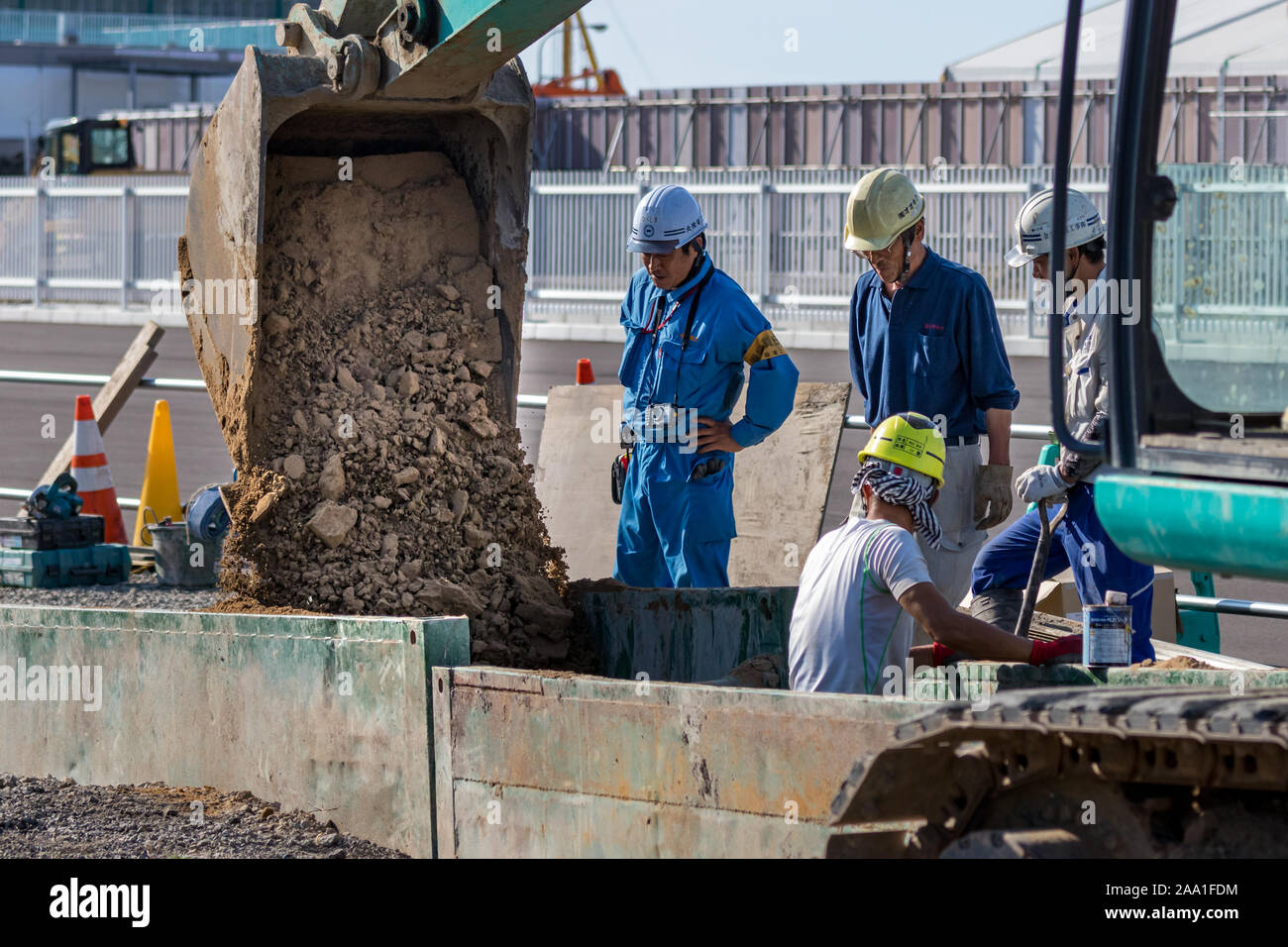 Group of japanese constructors working on the street using an excavator ...