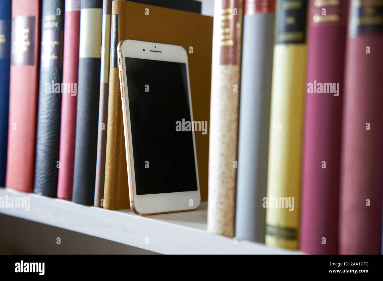 Sideview of mobile phone in bookshelf Stock Photo - Alamy