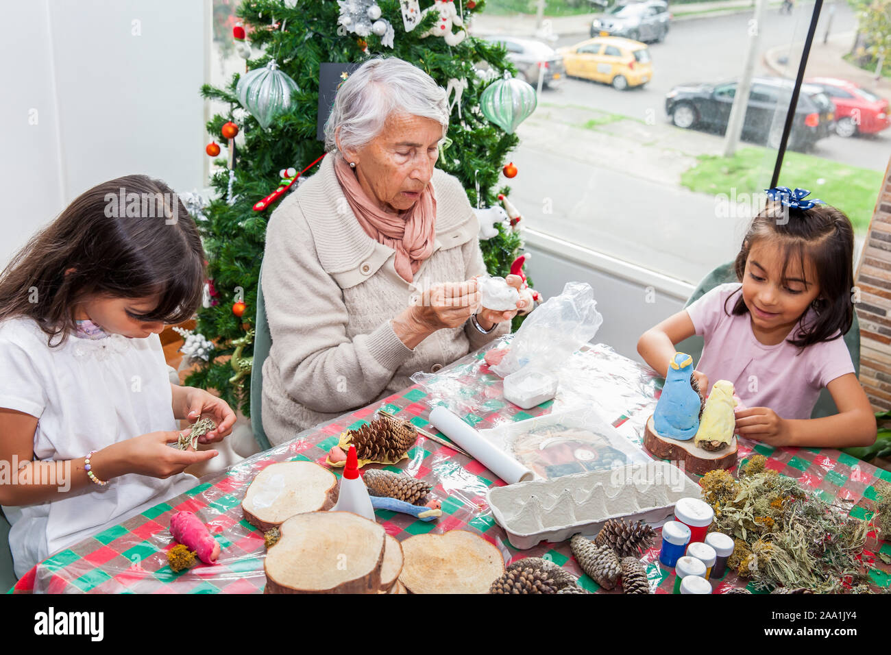 Grandmother teaching her granddaughters how to make christmas Nativity ...