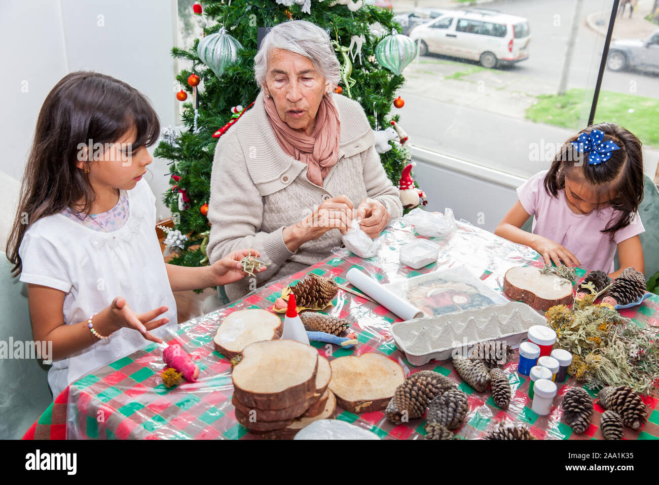 Grandmother teaching her granddaughters how to make christmas Nativity ...