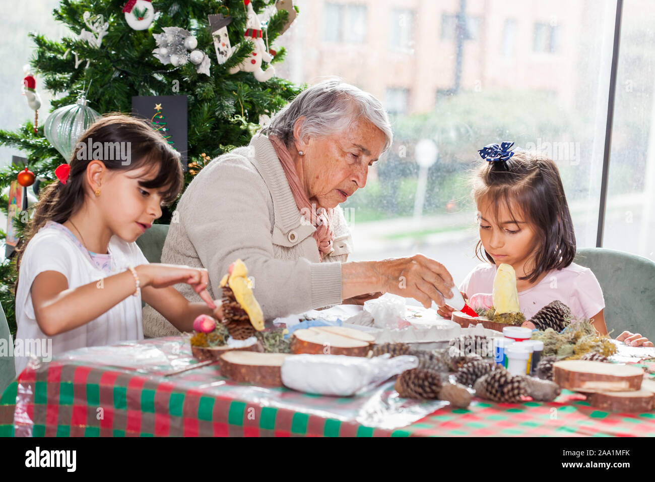 Grandmother teaching her granddaughters how to make christmas Nativity ...