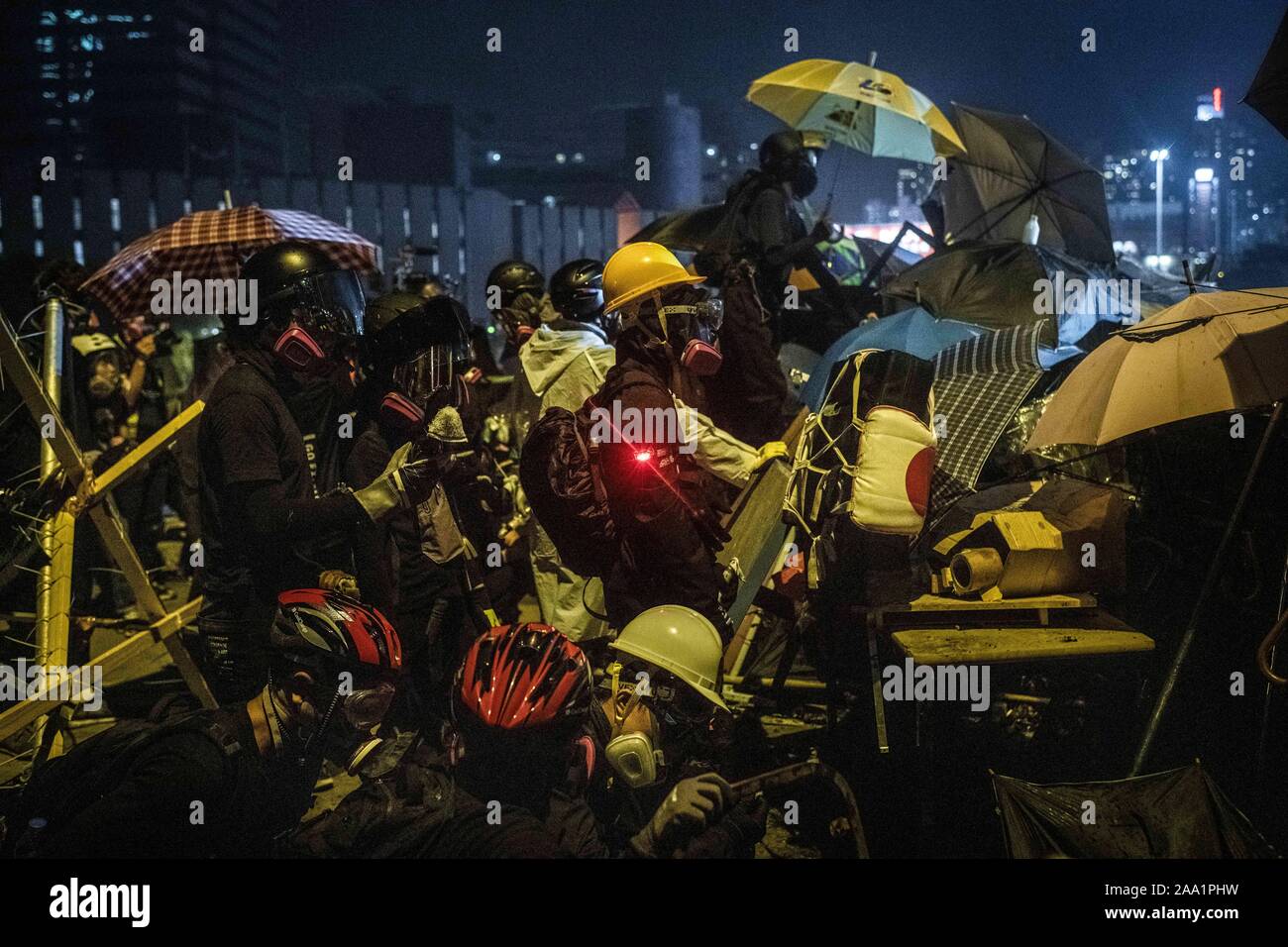 A group of frontline protesters gather behind a barricade to defend one ...