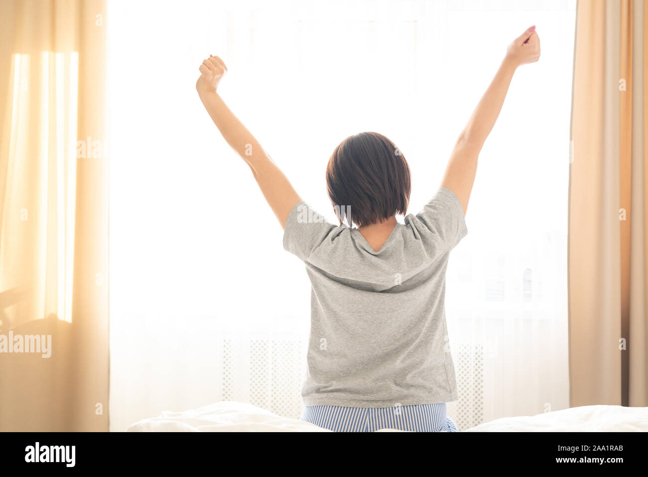 Woman stretching in bed after wake up, back view Stock Photo - Alamy