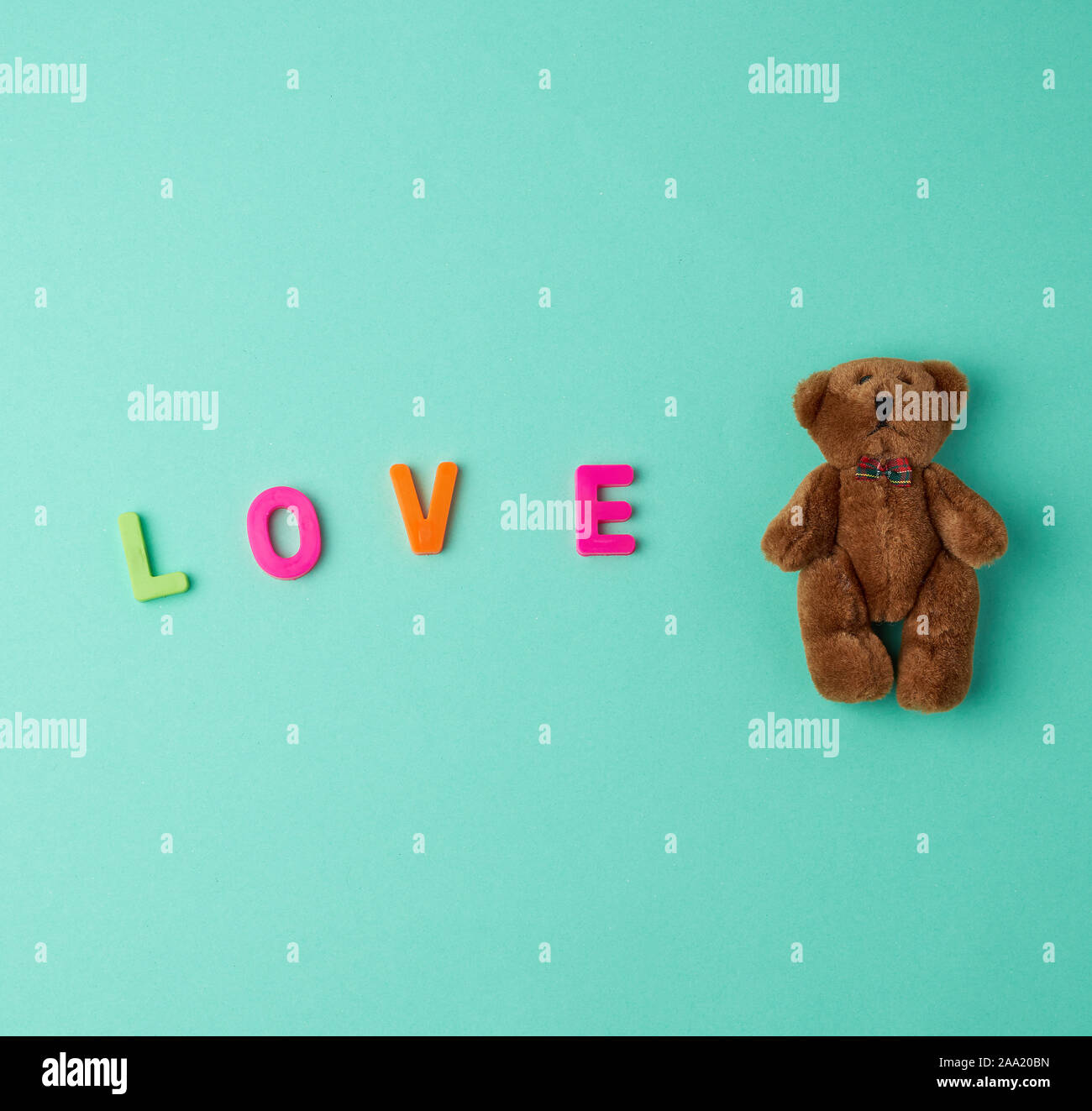 little cute brown teddy bear and the inscription love made of plastic ...
