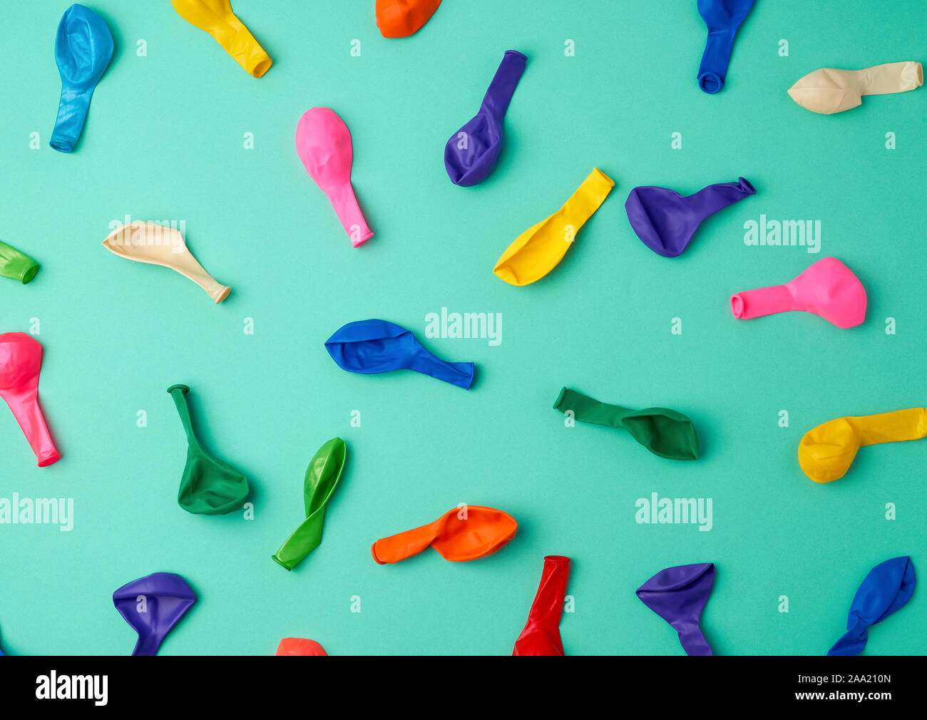 many deflated latex colorful balloons scattered on a green background ...