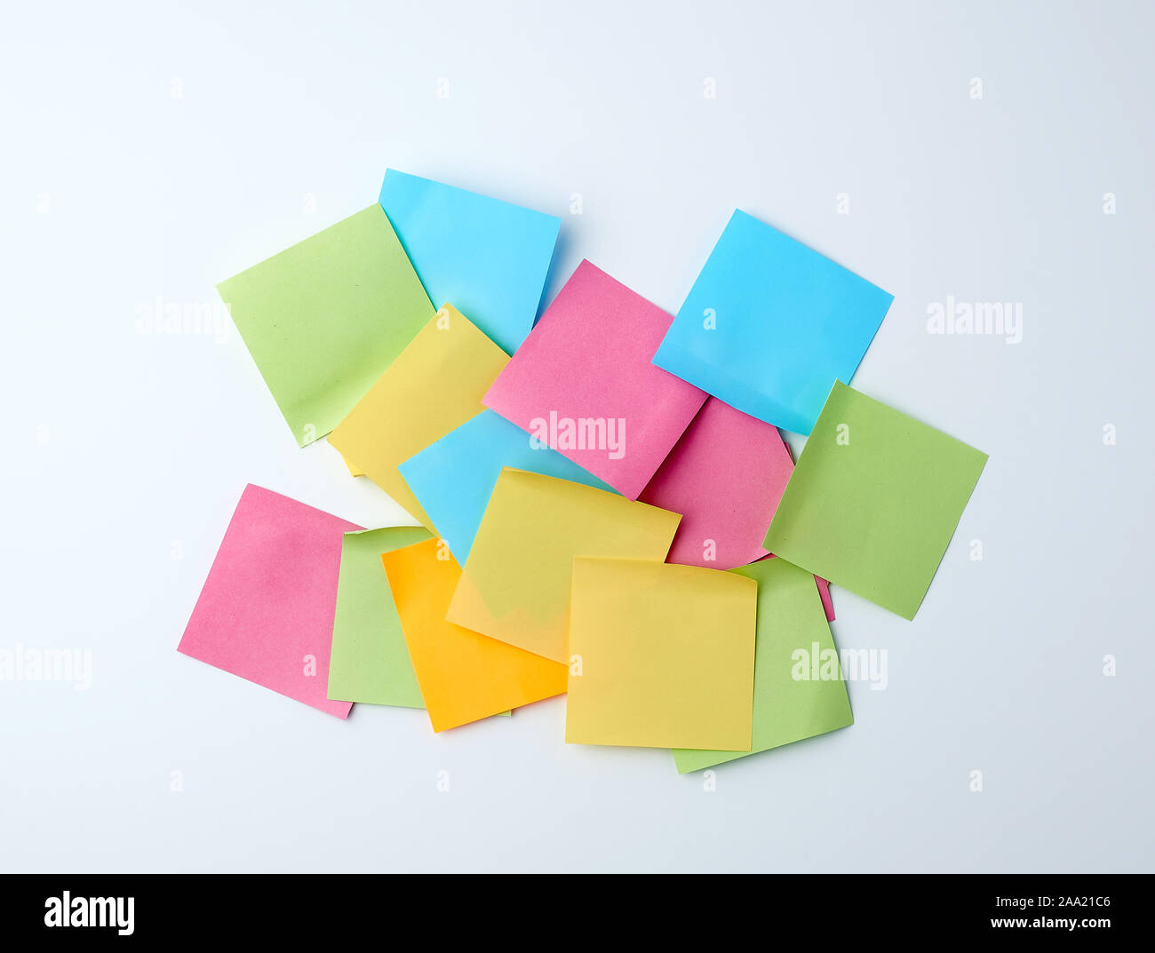 pile of multicolored paper square stickers on white background, top ...