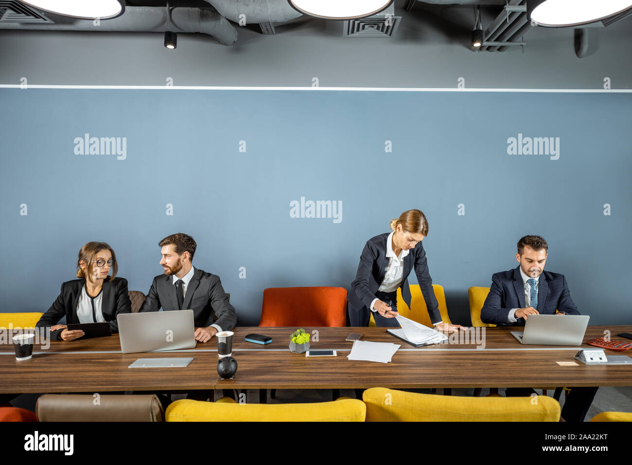 Business people working with laptops and documents, sitting in a row at ...