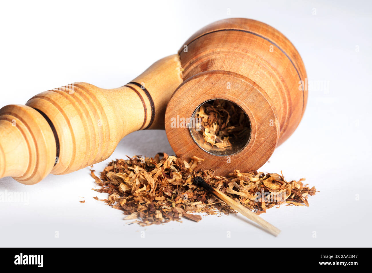 Close-up wooden smoking pipe with tobacco and burned matches on a white ...