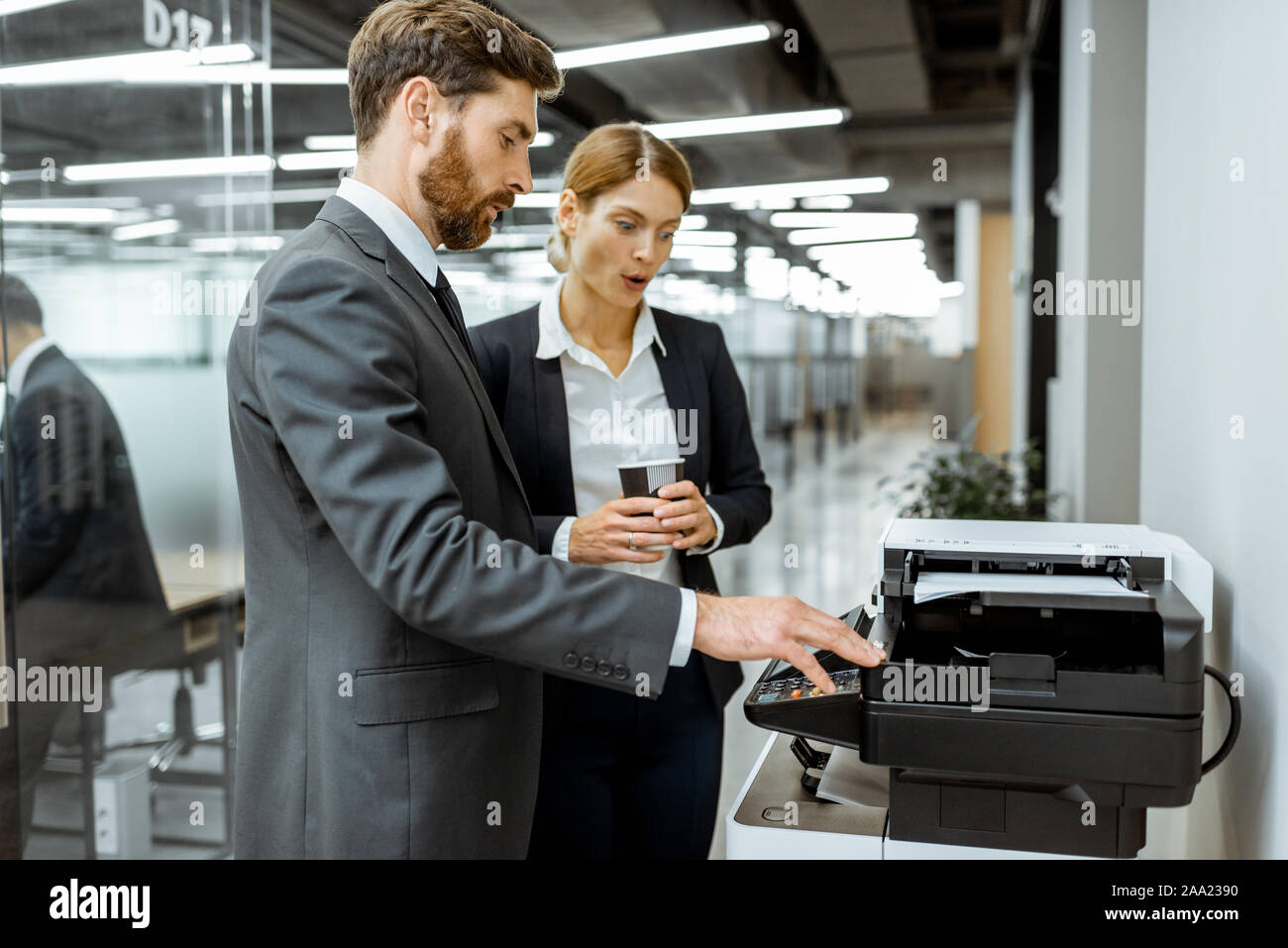Business man and woman talking near the copier during a coffee break in ...