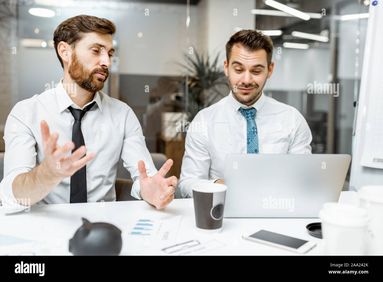 Two male employees in white shirts and tie having some business ...