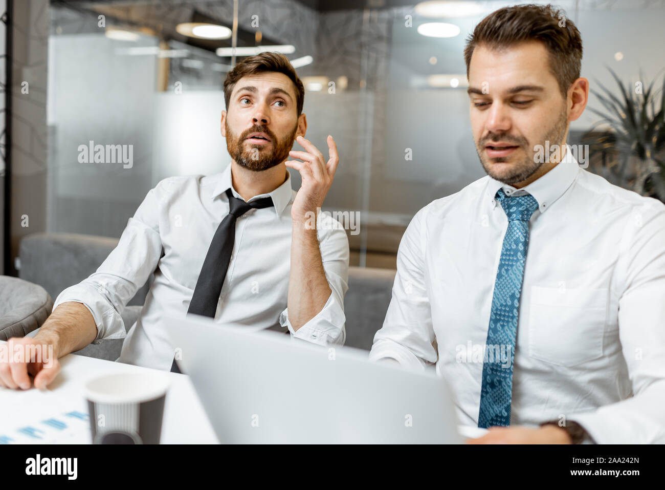 Two male employees in white shirts and tie having some business ...