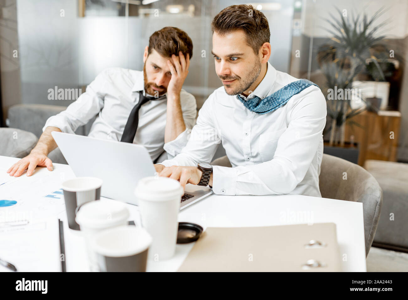 Two exhausted and tired employees hard working with laptop in the ...