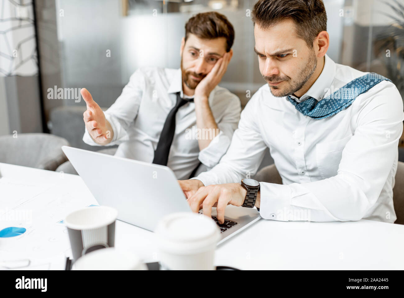 Two exhausted and tired employees hard working with laptop in the ...