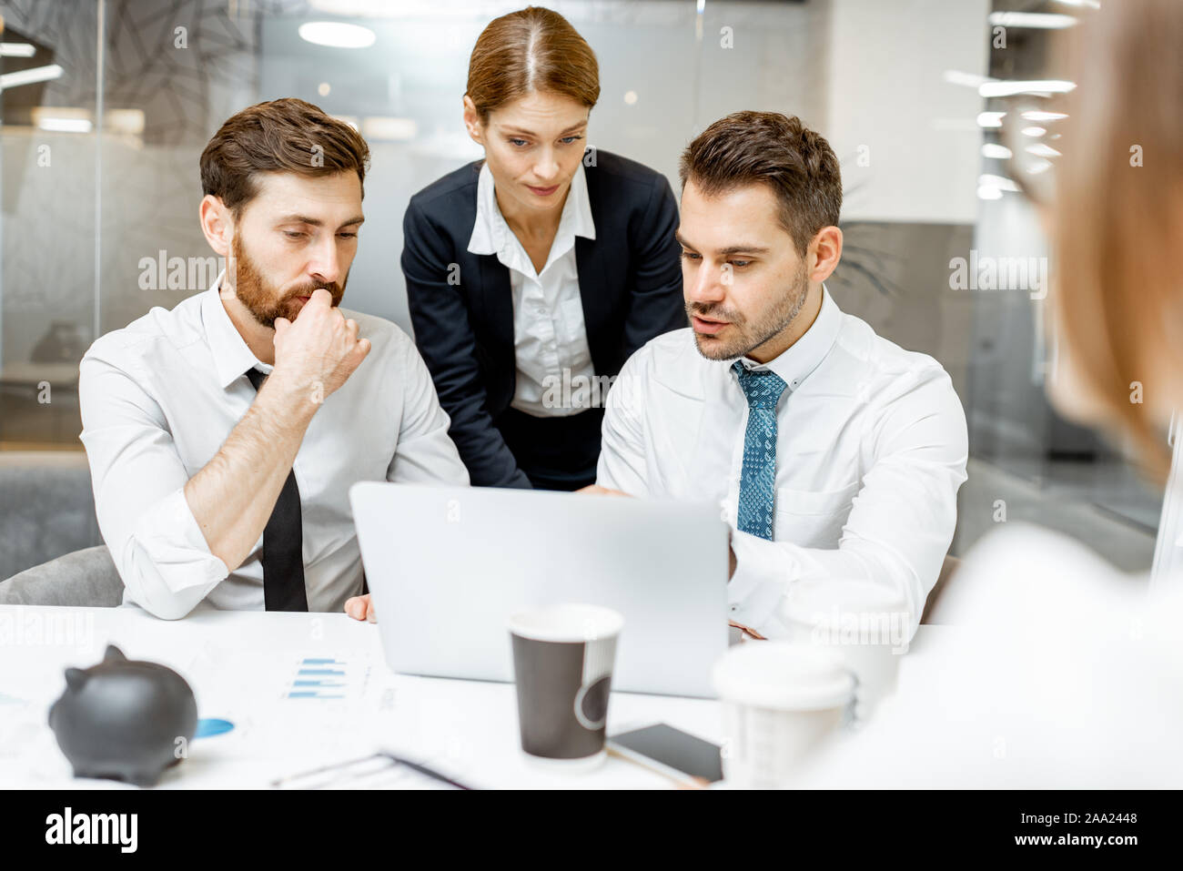 Team leader helping two male exhausted employees to do some work on a ...