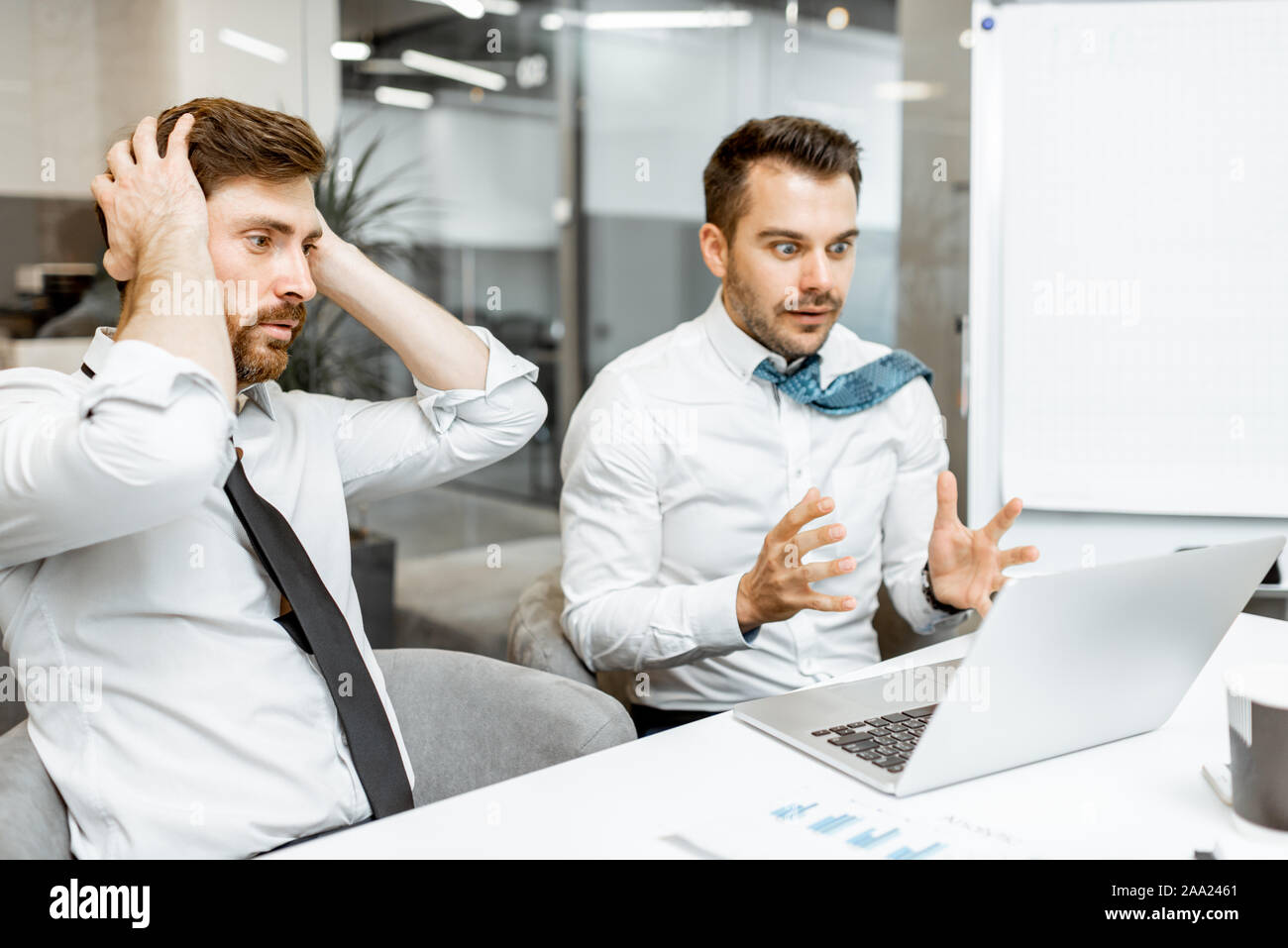 Two exhausted and tired employees hard working with laptop in the ...