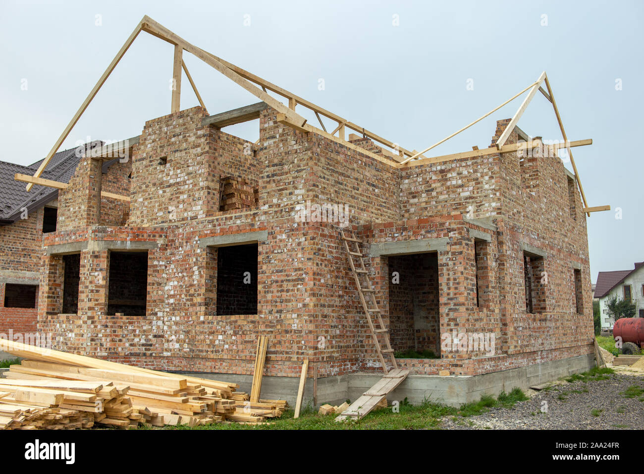 Unfinished brick house with wooden roof structure under construction ...