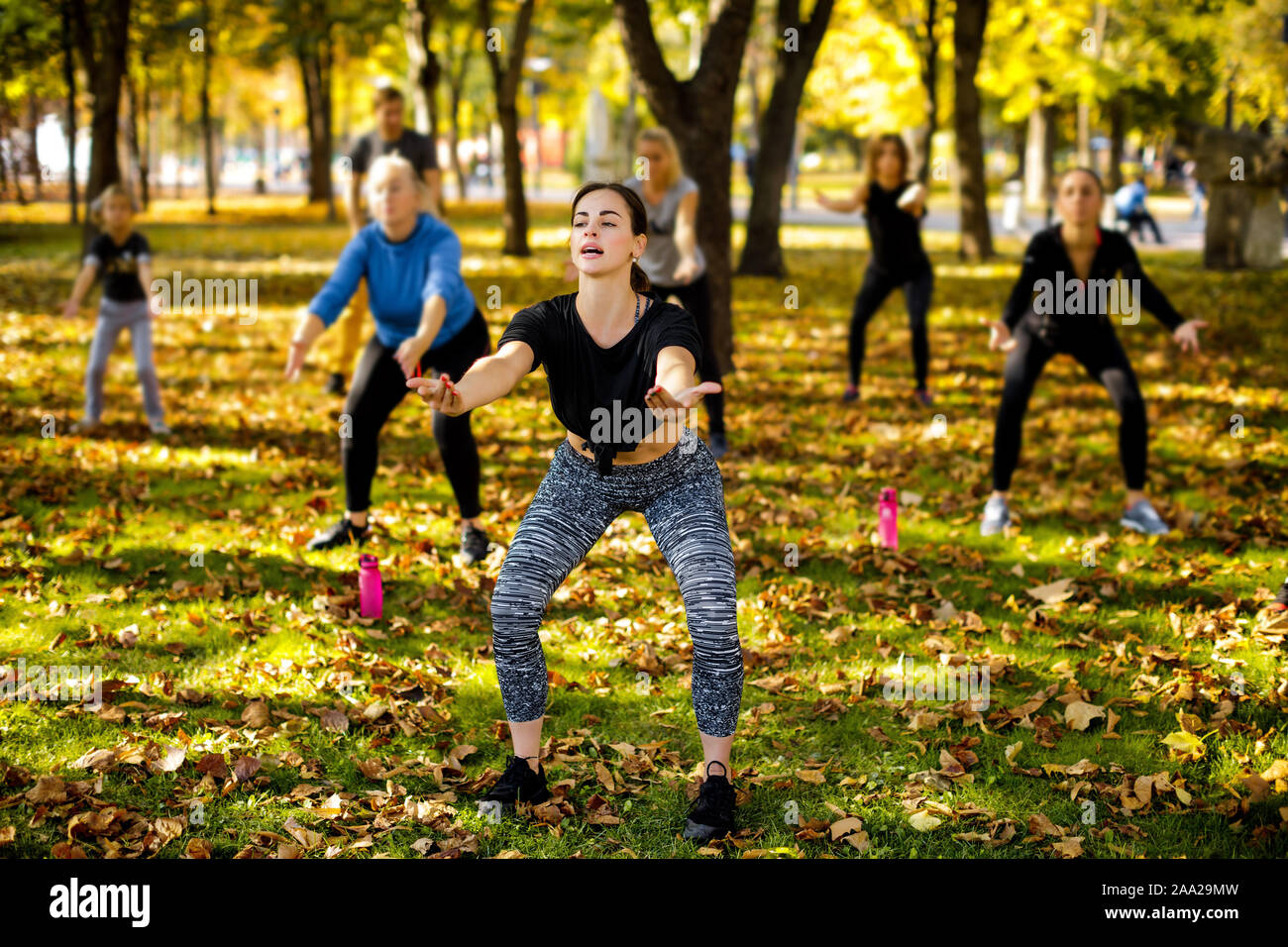 large group of people doing outdoor workout on green grass in park ...