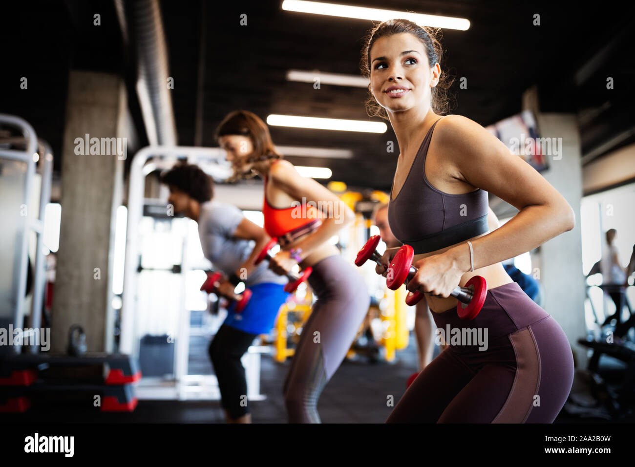 Healthy young people doing exercises at fitness studio Stock Photo - Alamy