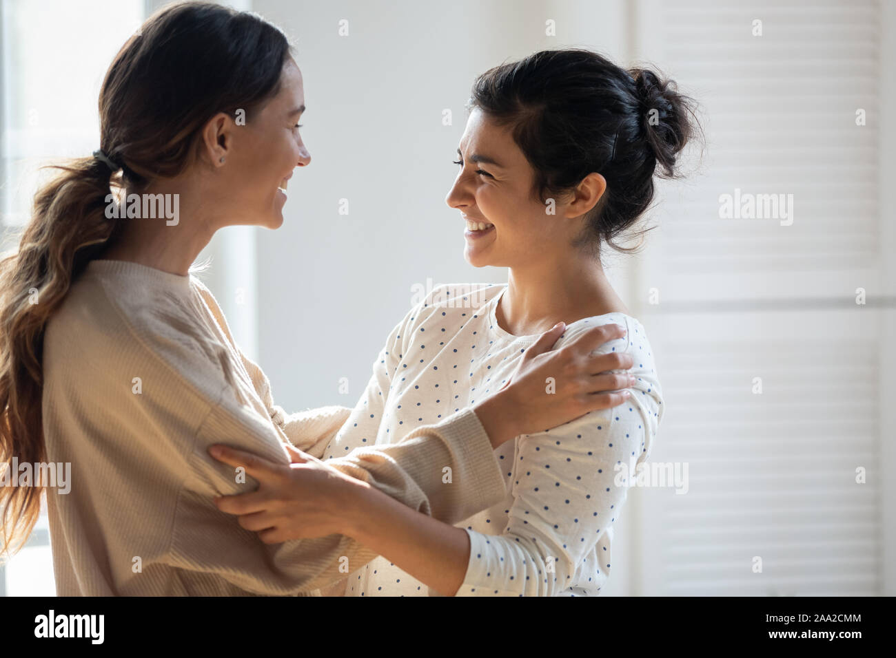 Two mixed race girls cuddling, enjoying communicating together Stock ...