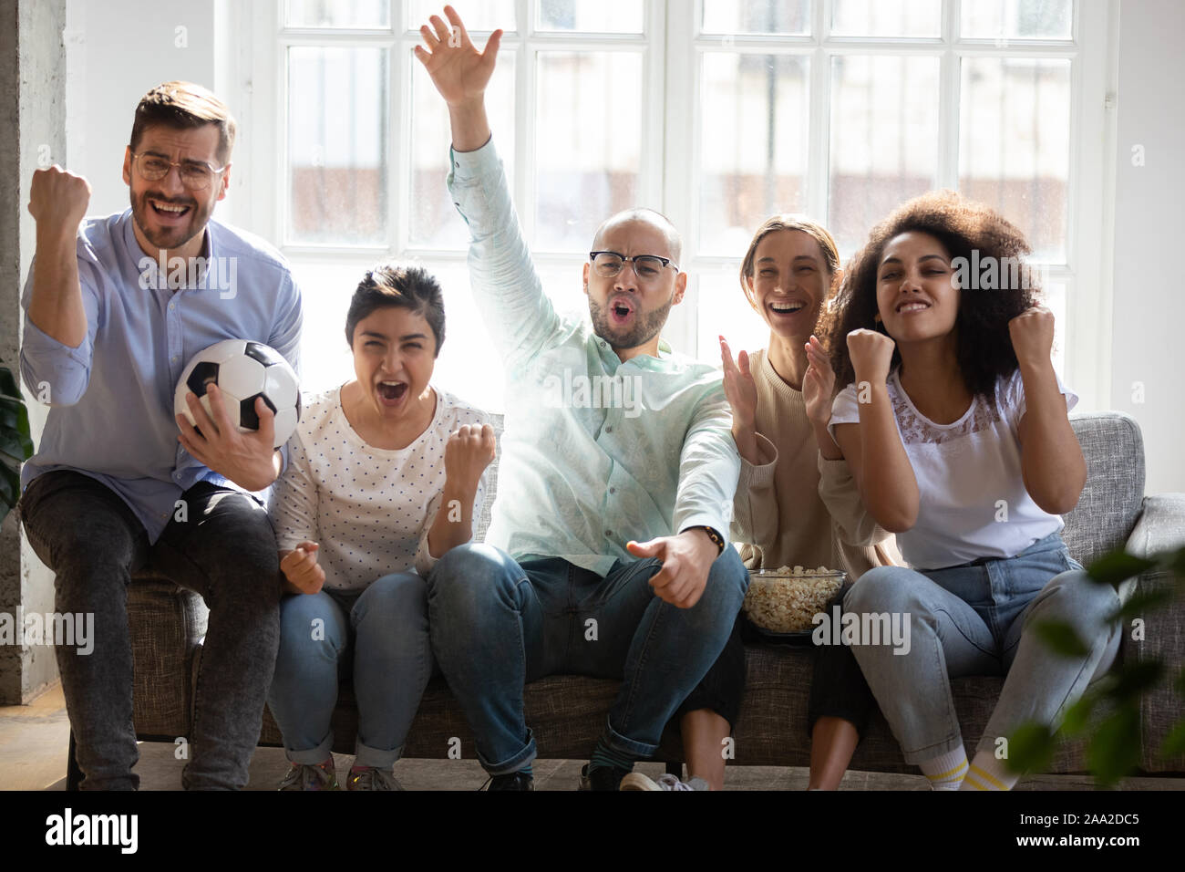 Overjoyed young mixed race football fans cheering favorite team Stock ...