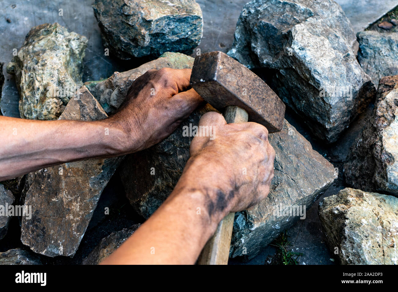 The dirty hands of a slave hold a hammer among the stones. Slave hard ...