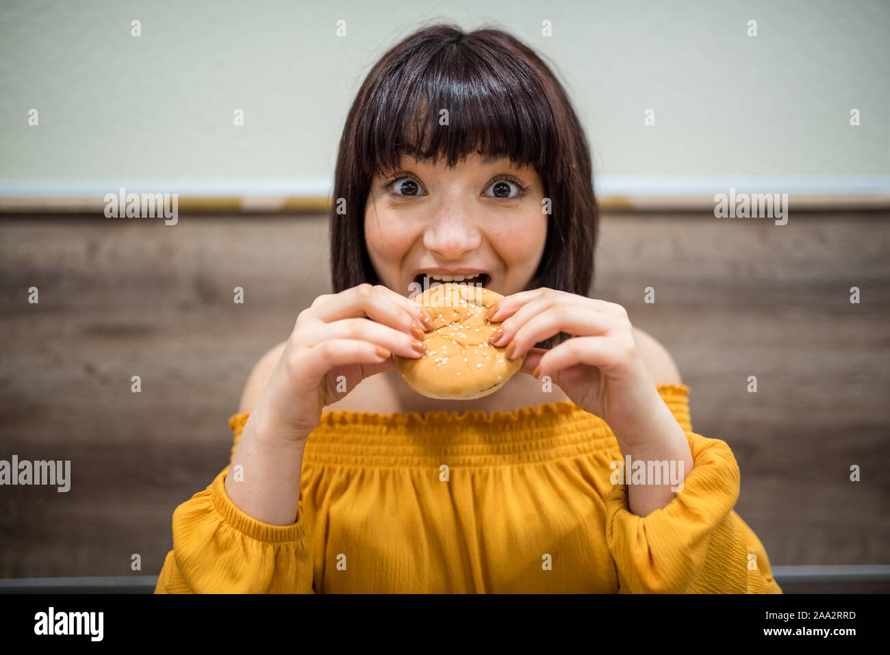 Beautiful young cute girl in fashionable clothes enjoys fast food ...