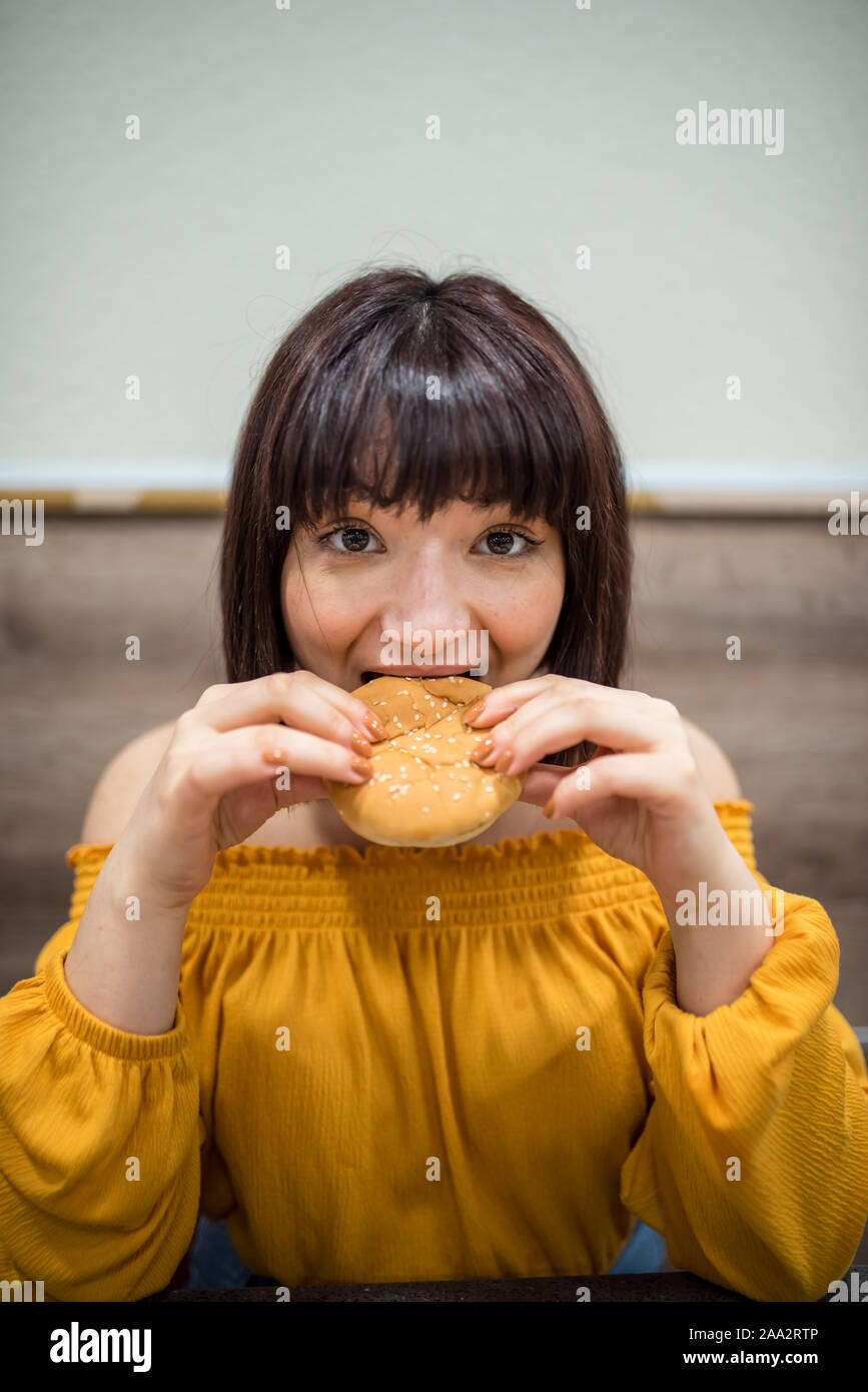 Beautiful young cute girl in fashionable clothes enjoys fast food ...