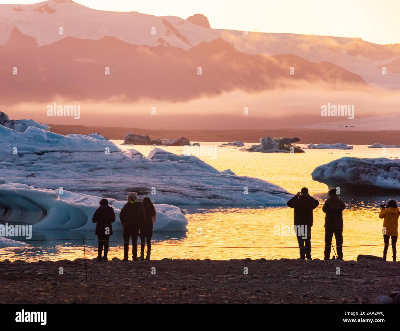 Ice Lagoon. Silhouette of tourists taking photo of sunset Ice lagoon ...