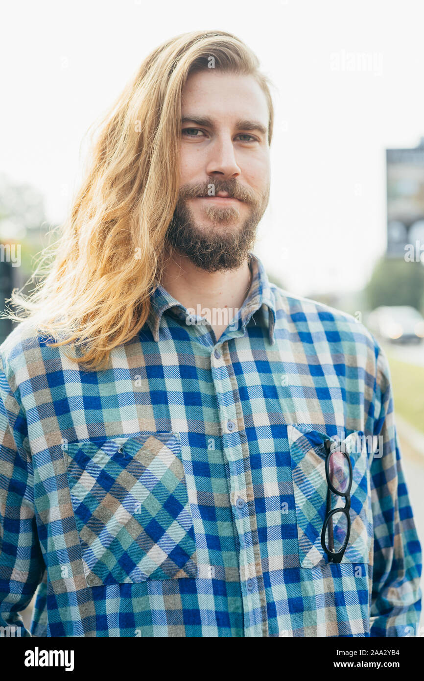 Portrait young beautiful bearded long hair man outdoor looking camera ...