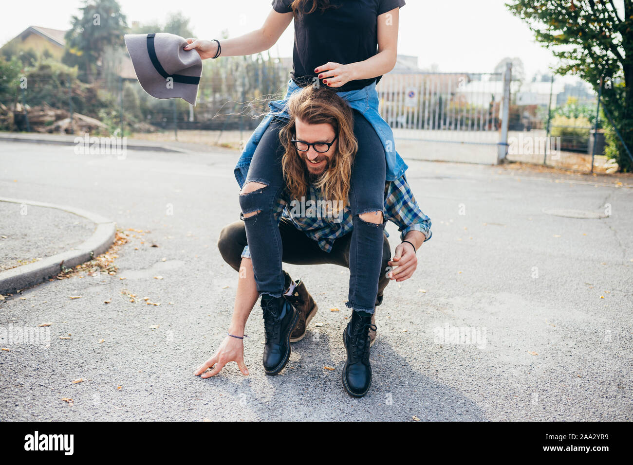 Young woman shoulder riding her bearded boyfriend outdoor throughfare ...
