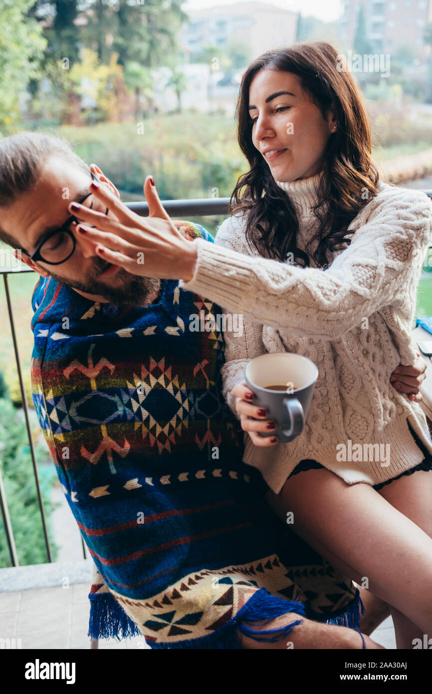 Young couple at home terrace having breakfast - she is sitting on his ...