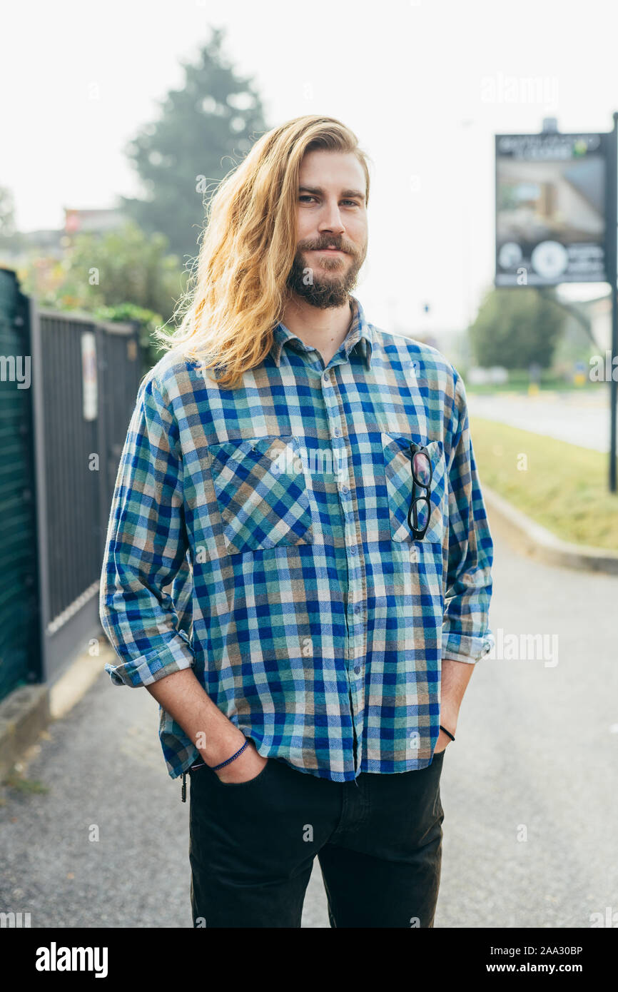 Young beautiful long hair bearded man outdoor posing looking camera ...