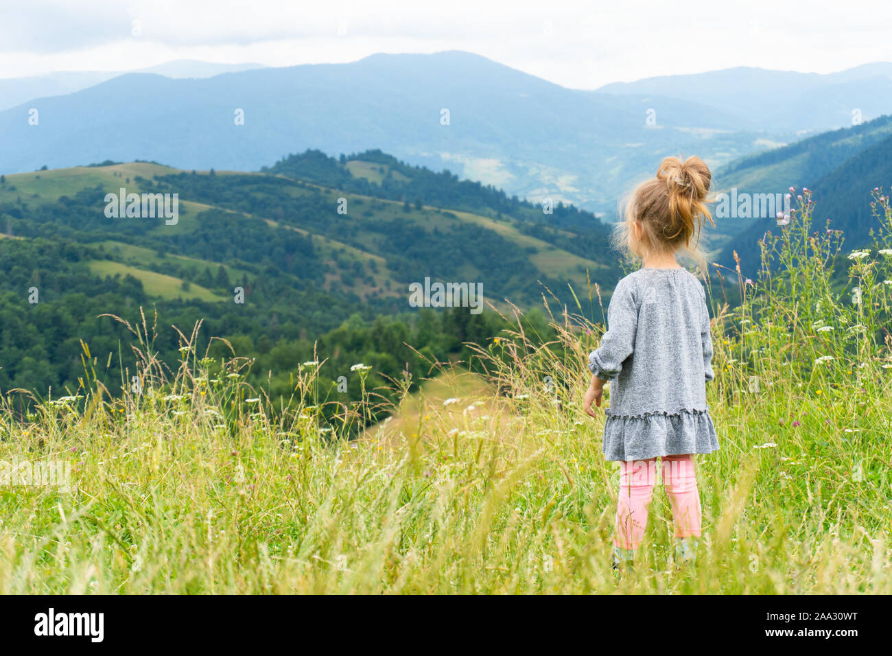Little girl standing outdoor and looking on mountains Stock Photo - Alamy