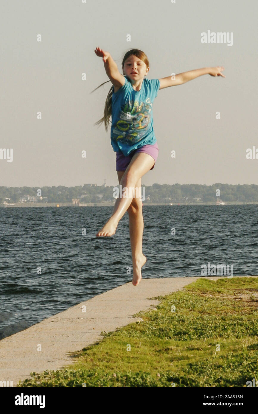Girl dancing on ledge small ledge by water Stock Photo - Alamy