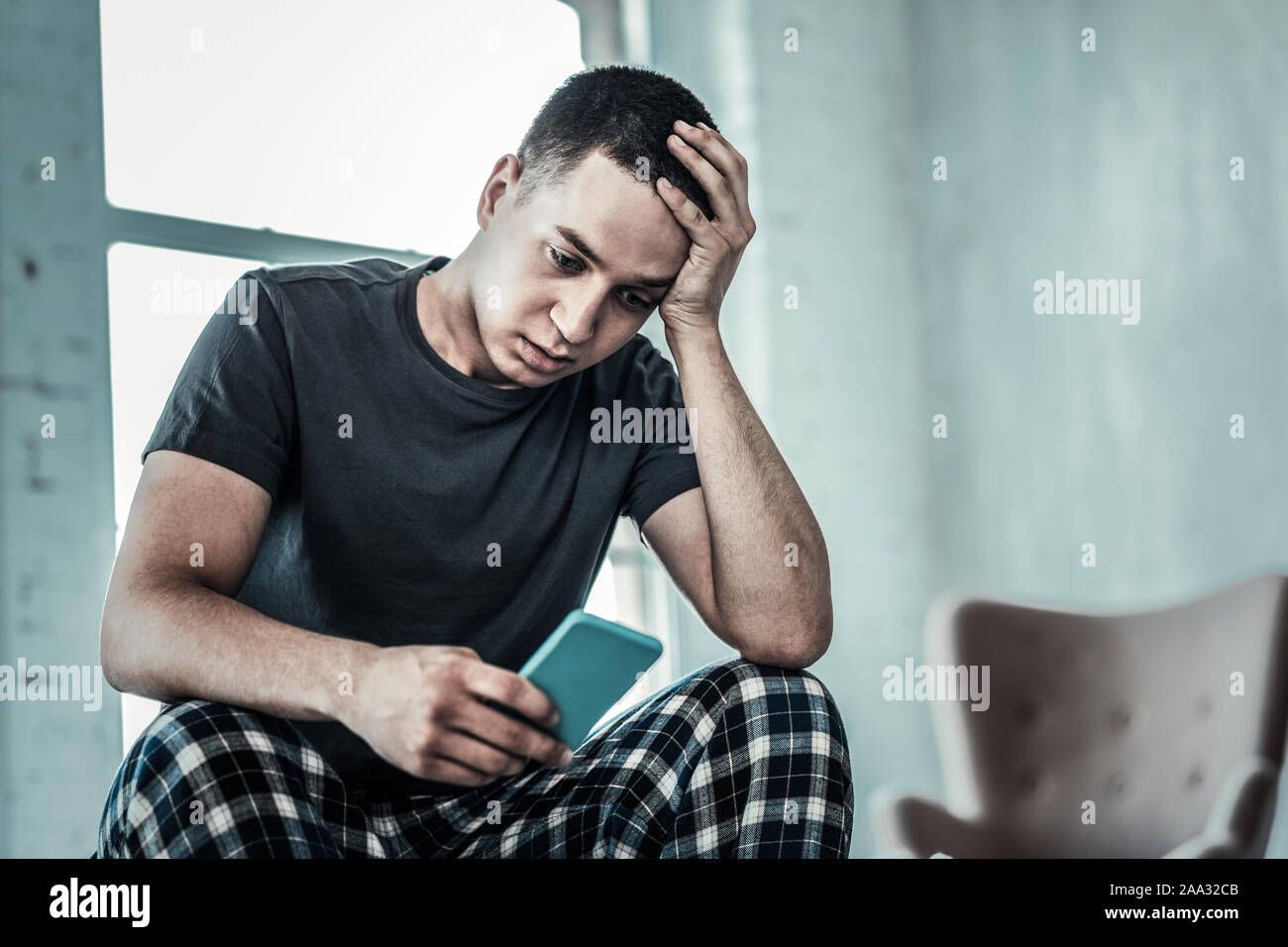 Sad unhappy man looking at his smartphone screen Stock Photo - Alamy