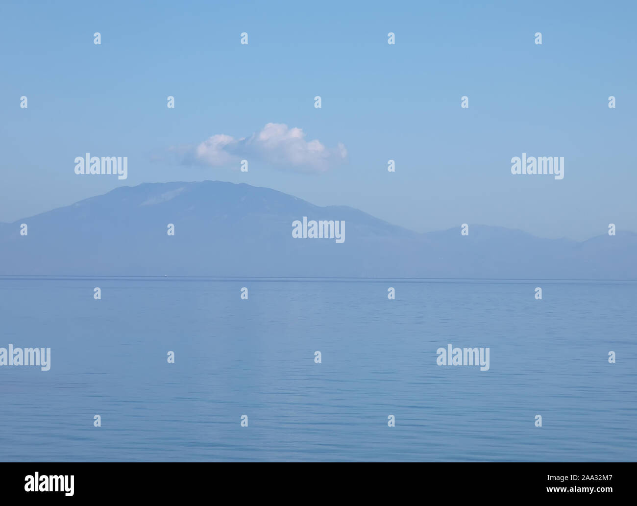 A very pale blue horizon showing sea, mountains and cloud suitable as a ...