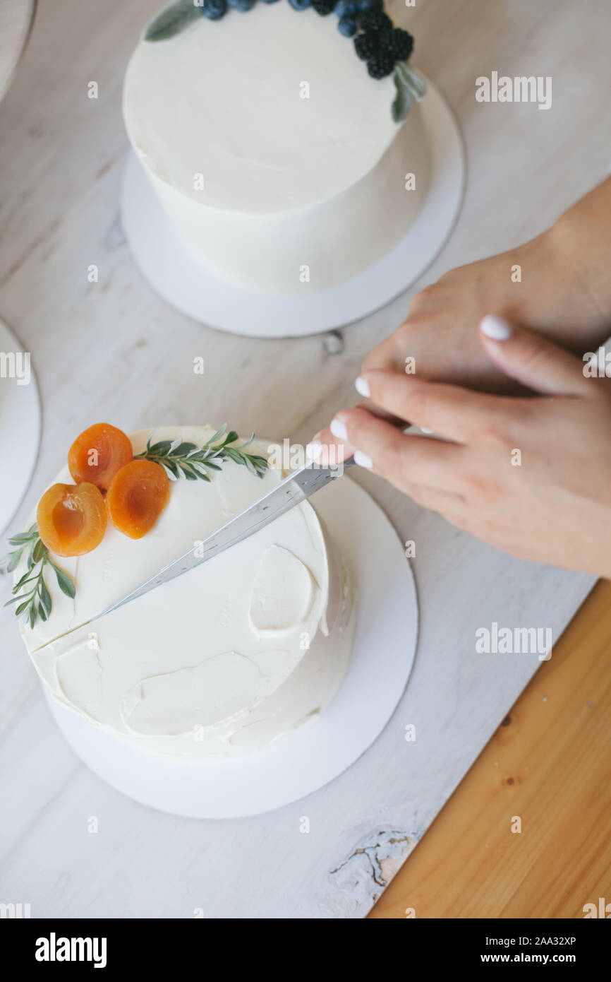 Woman cutting a cake with buttercream icing and peaches Stock Photo - Alamy