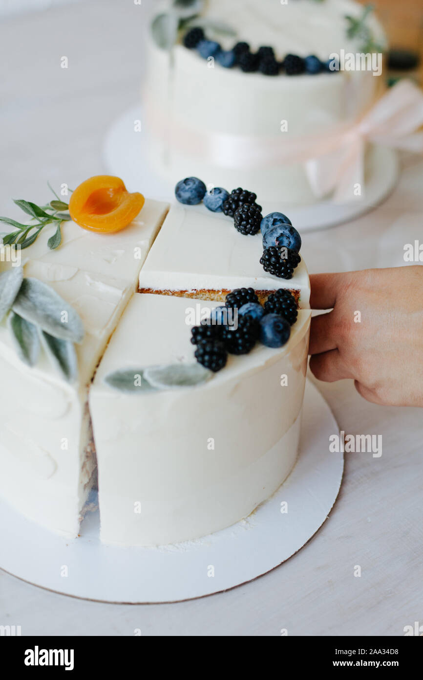 Woman putting together different slices of cake to make a compound cake ...
