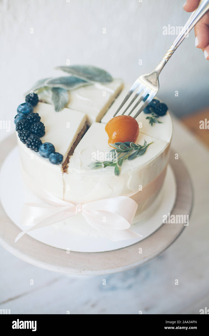 Woman eating peach off the top of a cake with buttercream icing and ...