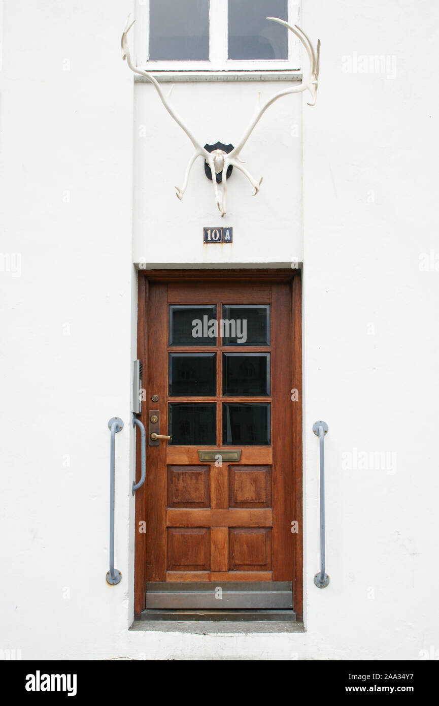 Entrance to a white facade building with a brown wooden door and elk ...