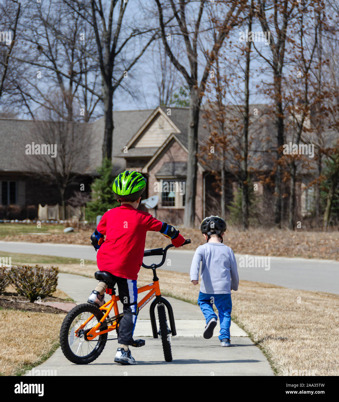Two kids playing-one riding his bicycle and the other running Stock ...