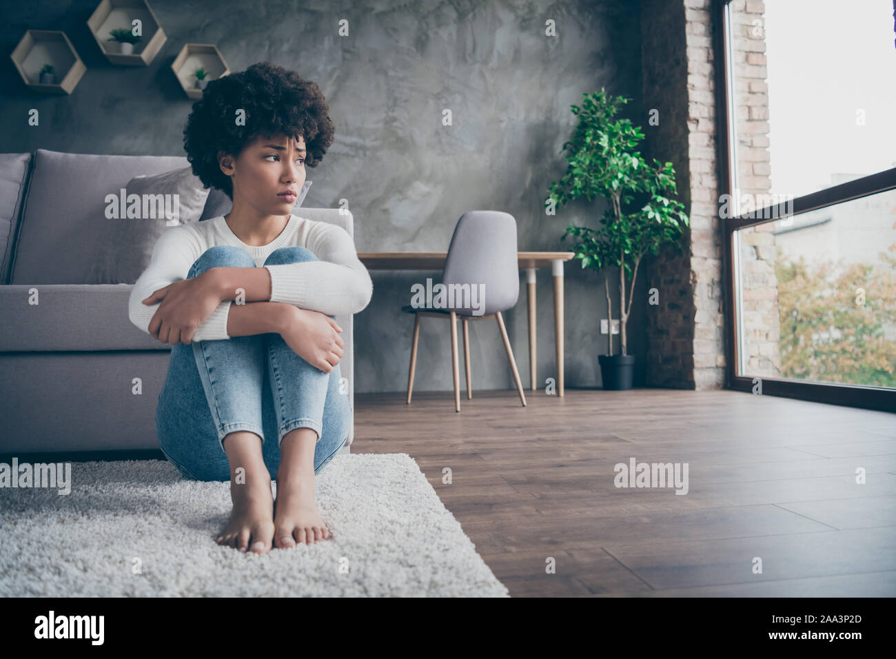 Photo of pretty dark skin curly lady sitting floor near sofa sad ...