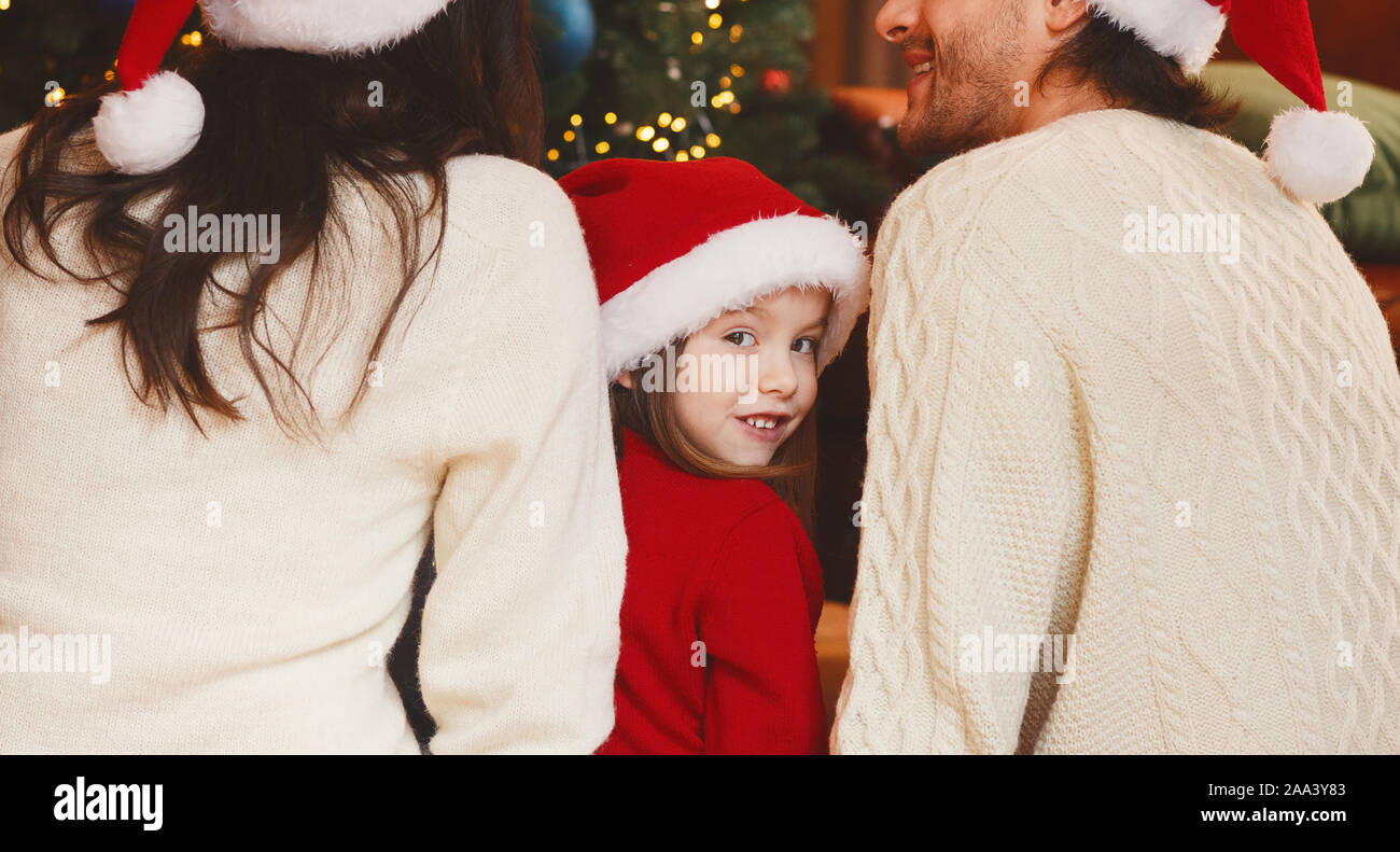 Little girl in Santa hat looking at camera over shoulder Stock Photo ...