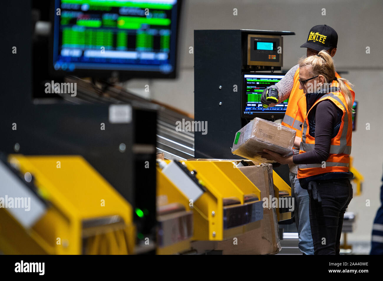 Cologne, Germany. 19th Nov, 2019. DHL employees scan a parcel at the ...