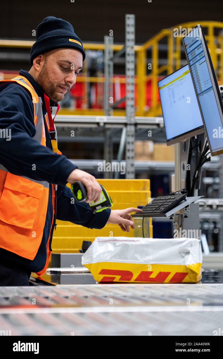 Cologne, Germany. 19th Nov, 2019. A DHL employee scans a parcel at the ...