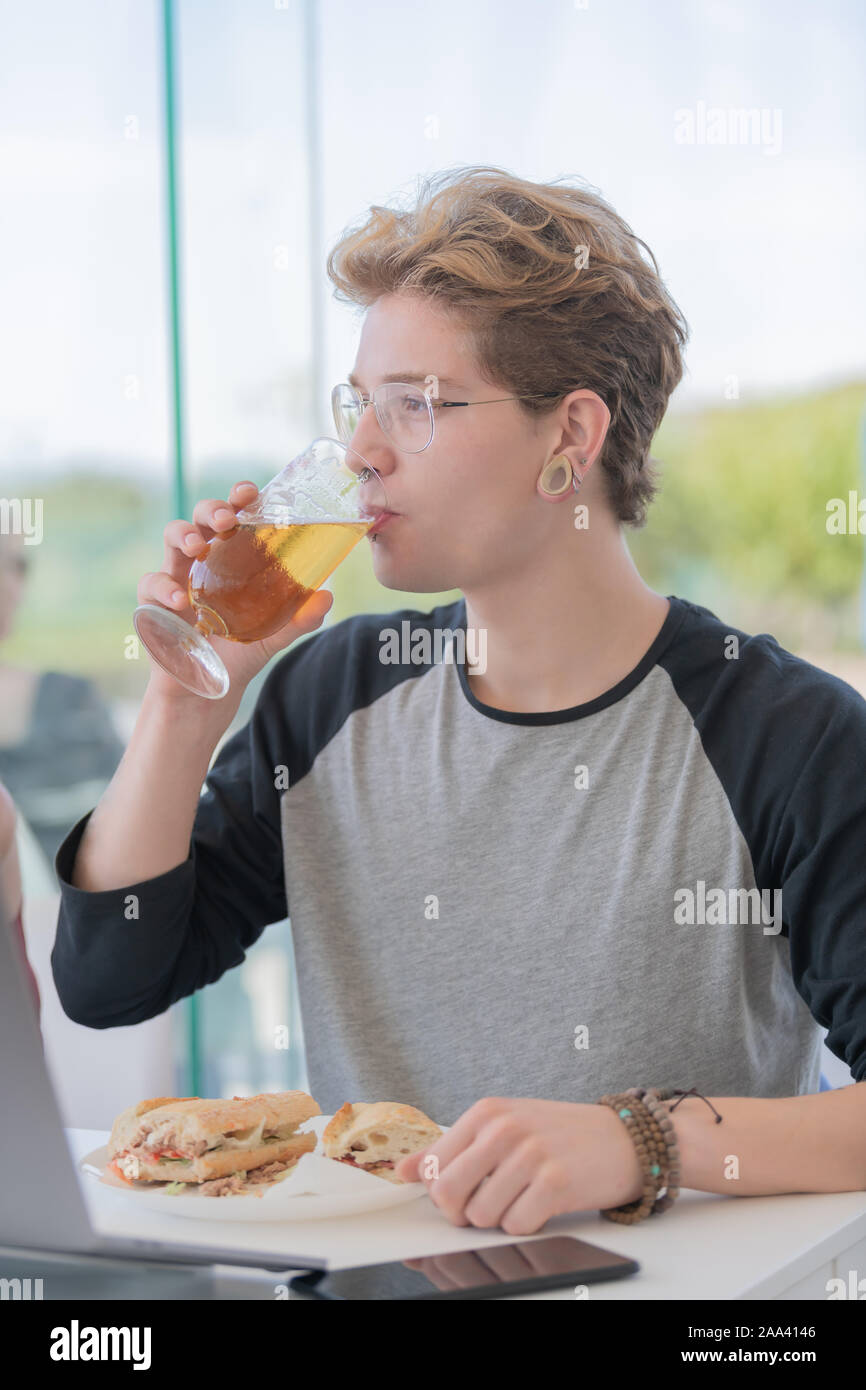 Man drinking beer. Side view of handsome young man drinking beer while ...